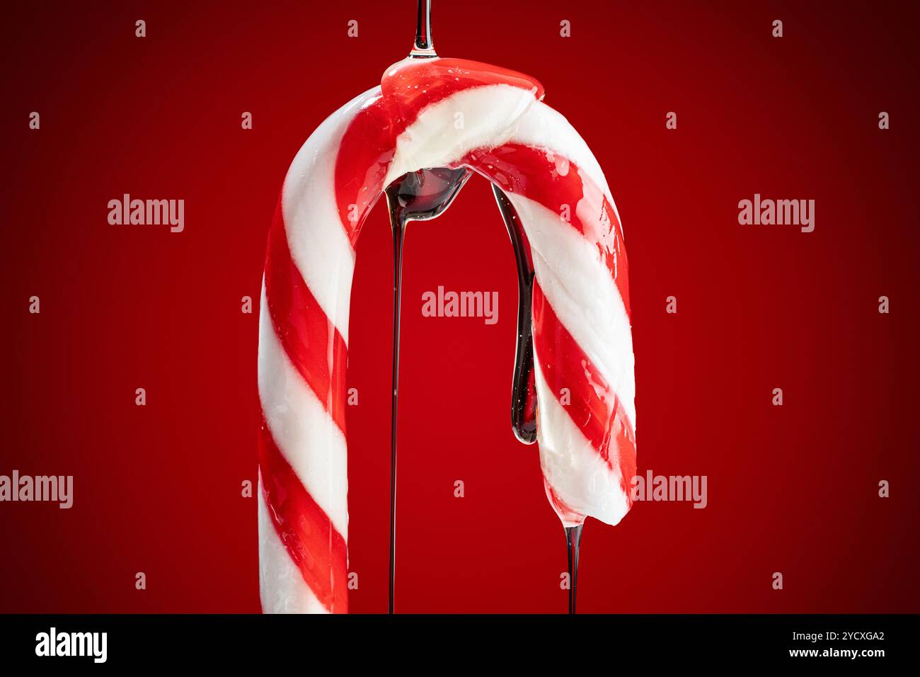A glossy syrup cascading over a classic candy cane, set against a deep ...