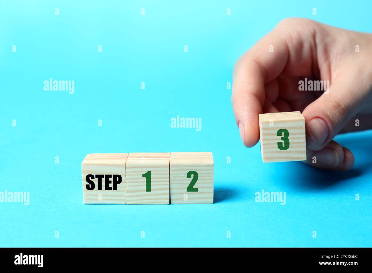 Woman putting wooden cube with digit 3 to row of other numbered ones on ...