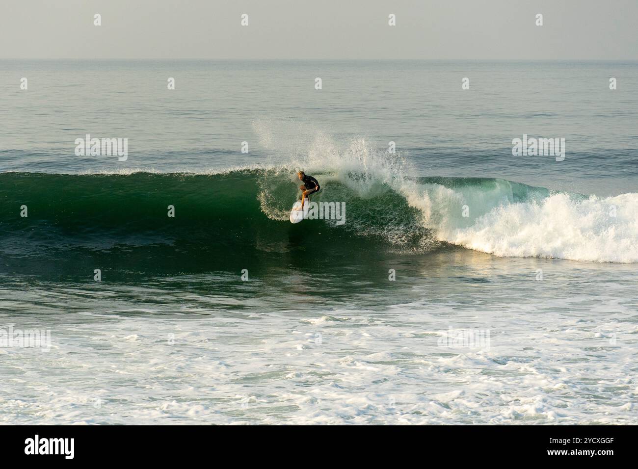 Unrecognizable surfer riding a green wave in the serene Pacific Ocean ...