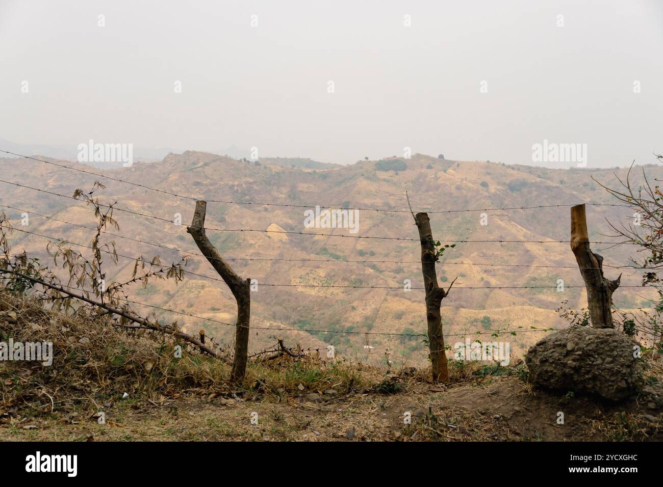 A rustic barbed wire fence stretches across a barren landscape ...