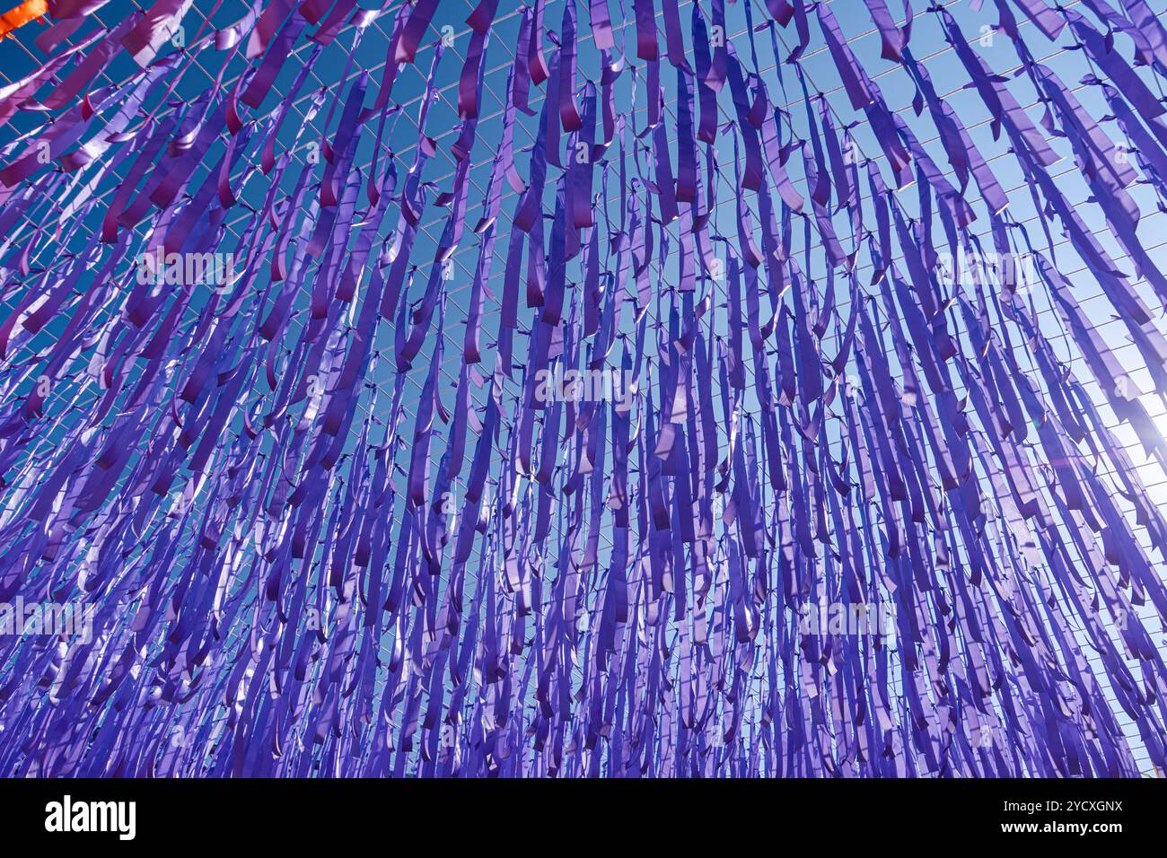 A dynamic display of purple ribbons hanging from above creates a ...