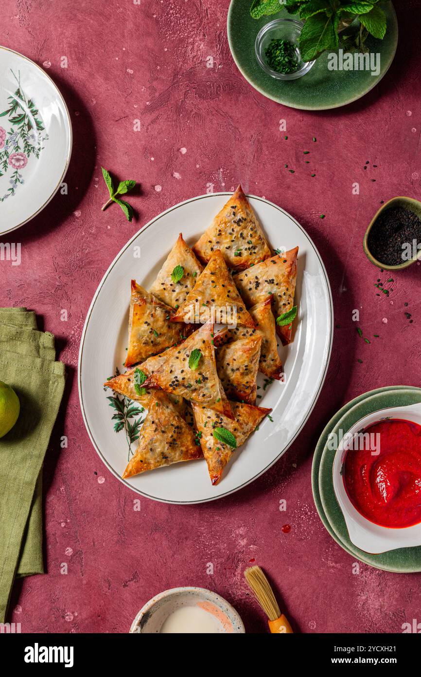 A plate of crispy baked samosas, sprinkled with sesame seeds and ...