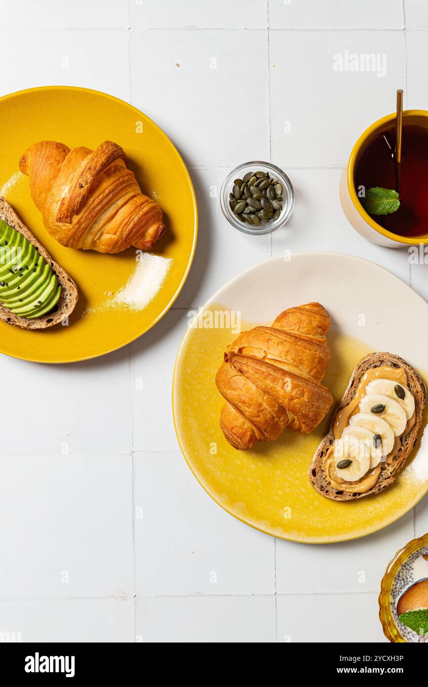 Breakfast setup featuring croissants, avocado toast, and banana peanut ...