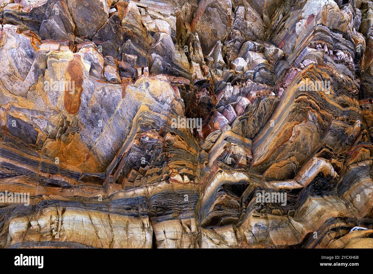 Textured layers of ancient sedimentary rocks forming jagged outcrops in ...