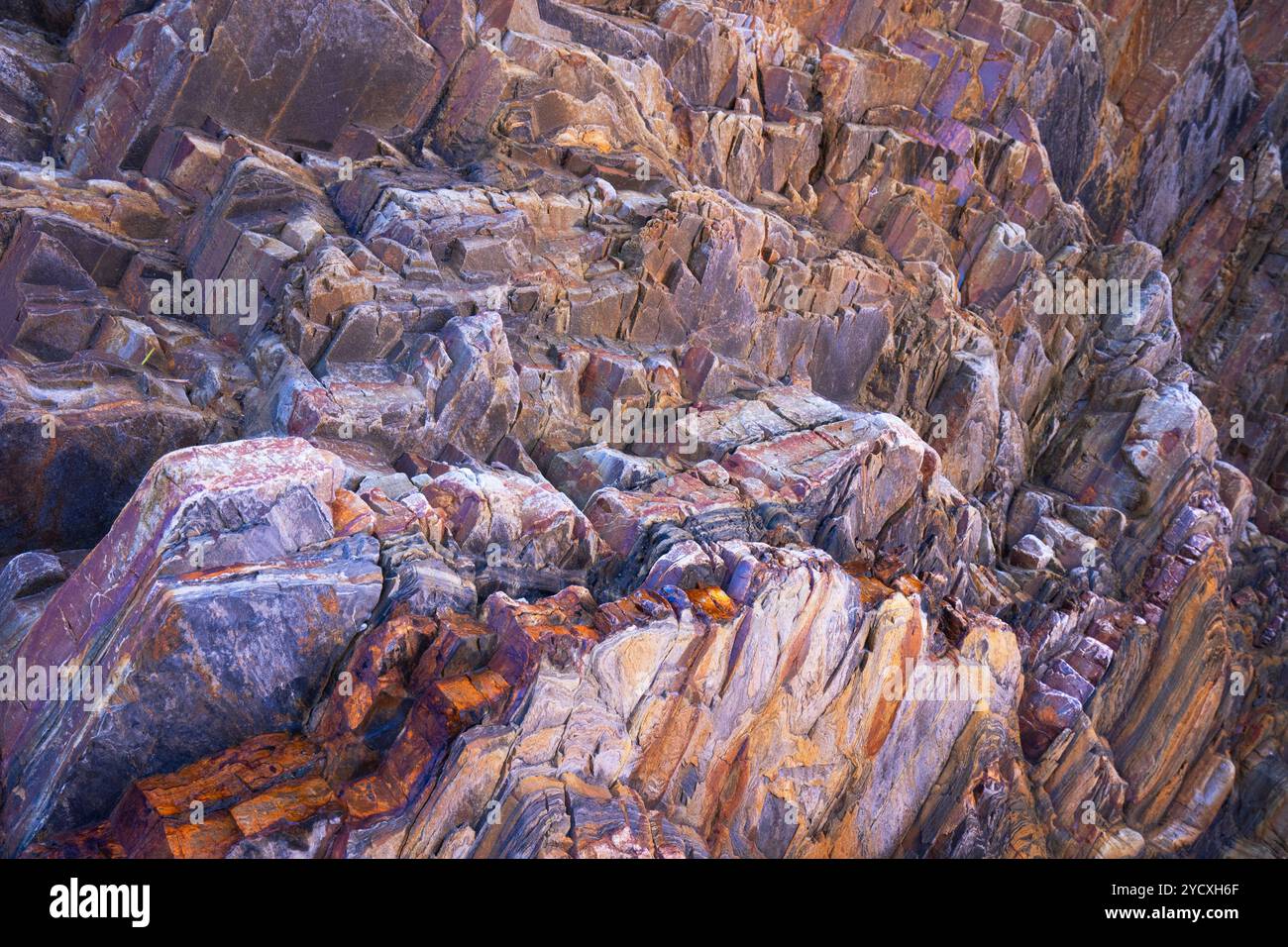 Textured layers of ancient sedimentary rocks forming jagged outcrops in ...