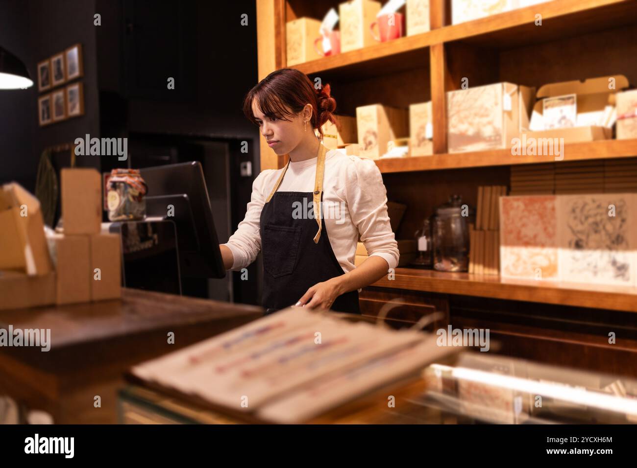 A young woman works diligently at the register in a quaint, well ...