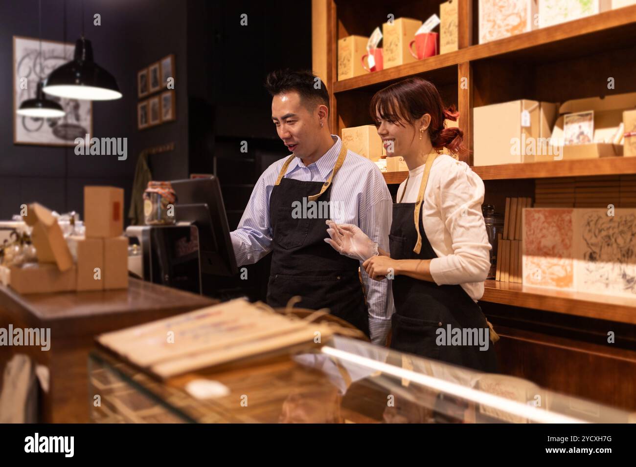 Two employees at a gourmet chocolate store collaborate behind the ...