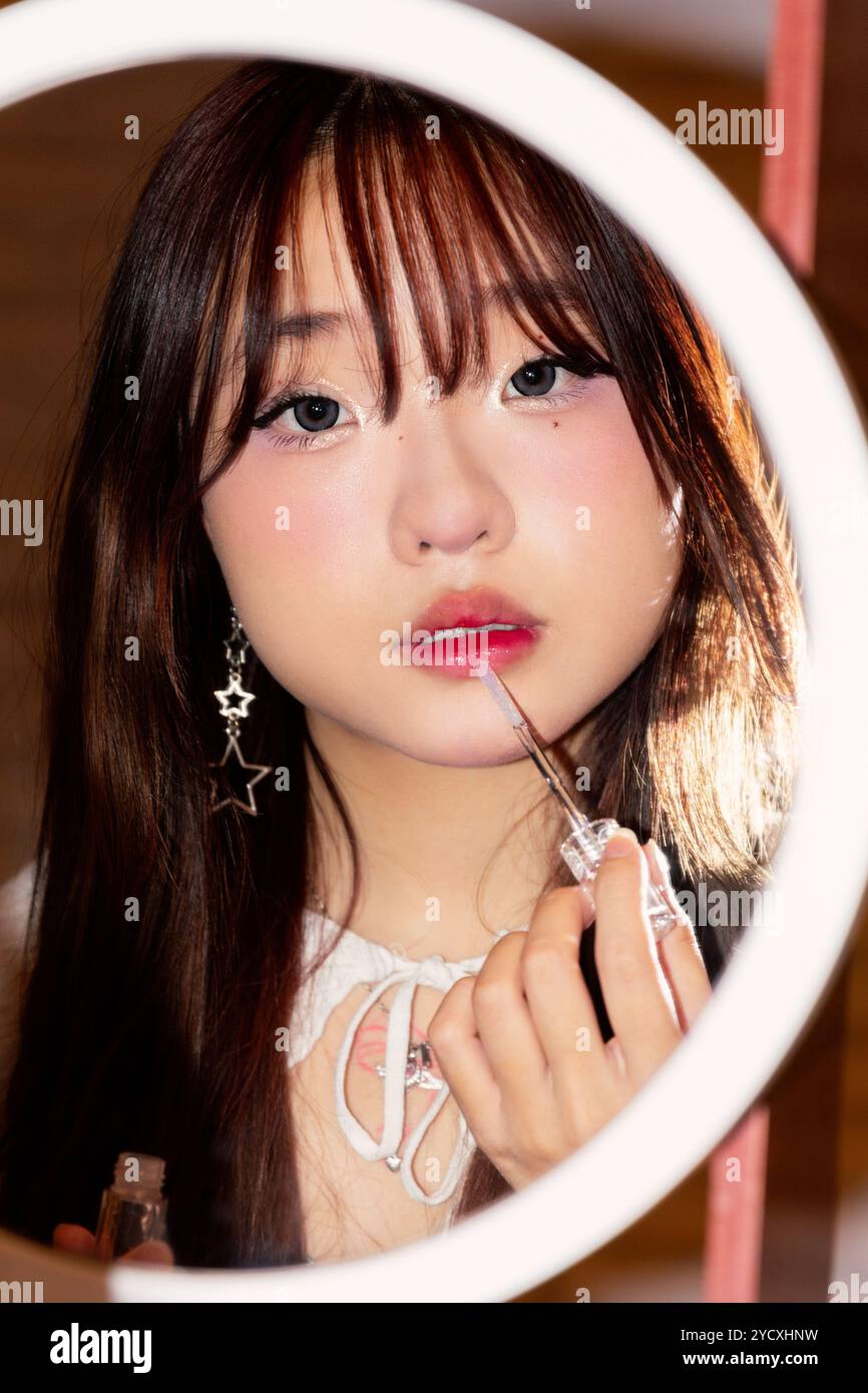 A young Chinese Gen Z girl subtly enhances her beauty by applying lip ...