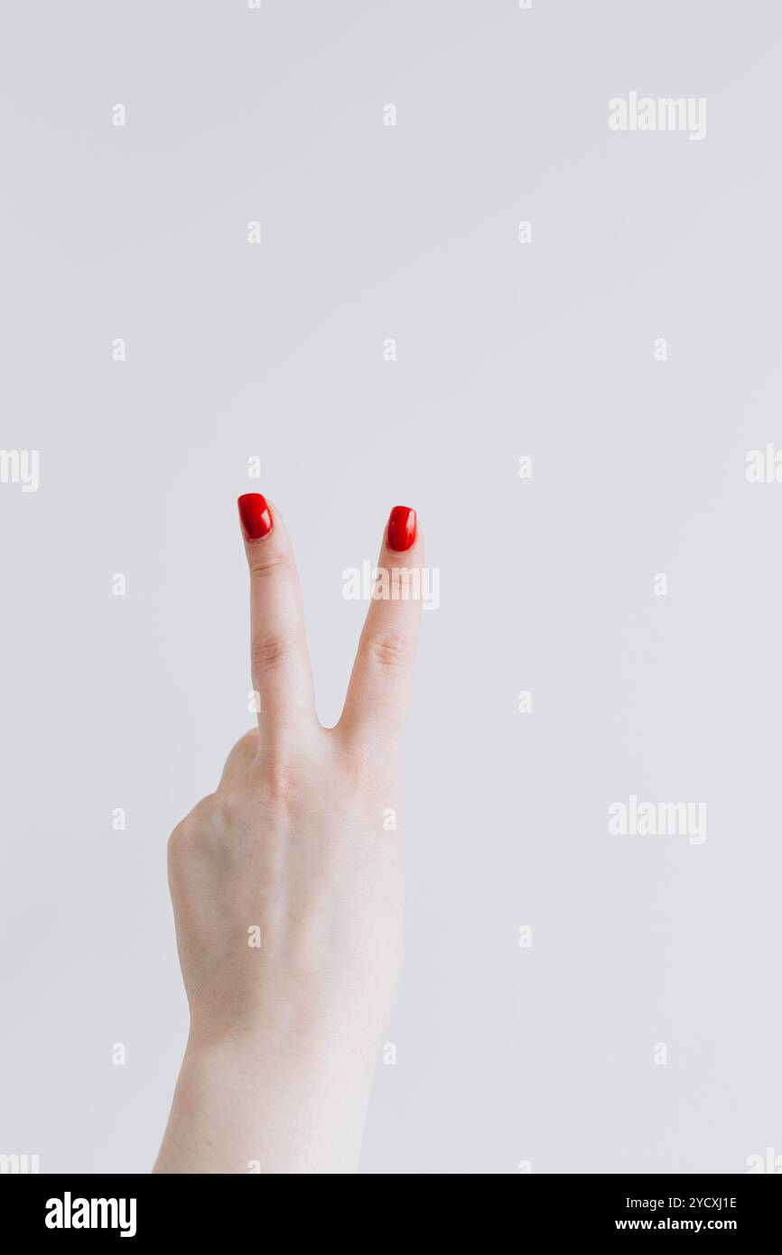 A close-up of a hand making the reverse V-sign with two fingers raised ...