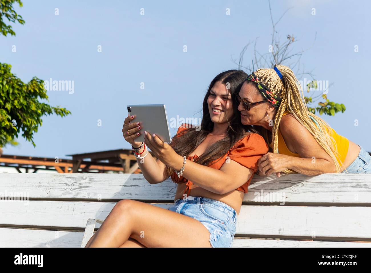 A loving mother and her transgender daughter, formerly her son, are happily using a digital ...