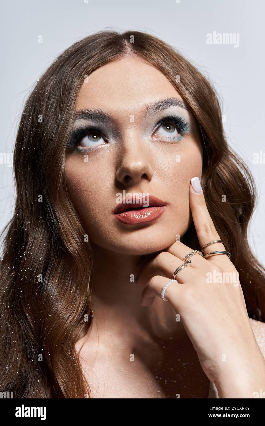 A young woman gazes thoughtfully upward while highlighting her striking ...