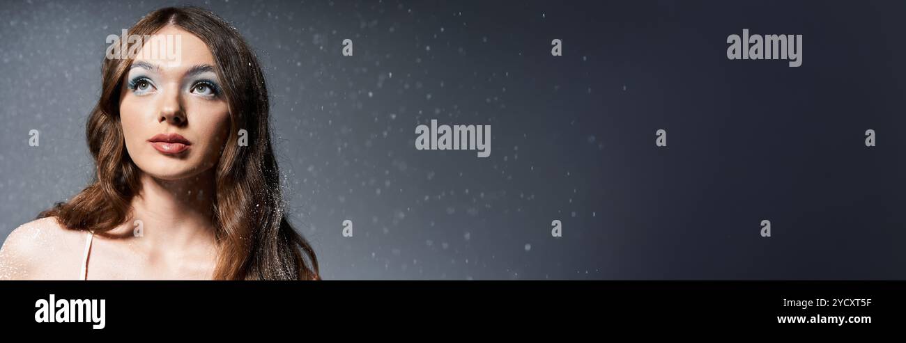 The young woman stands elegantly, gazing in wonder as soft sparkles ...