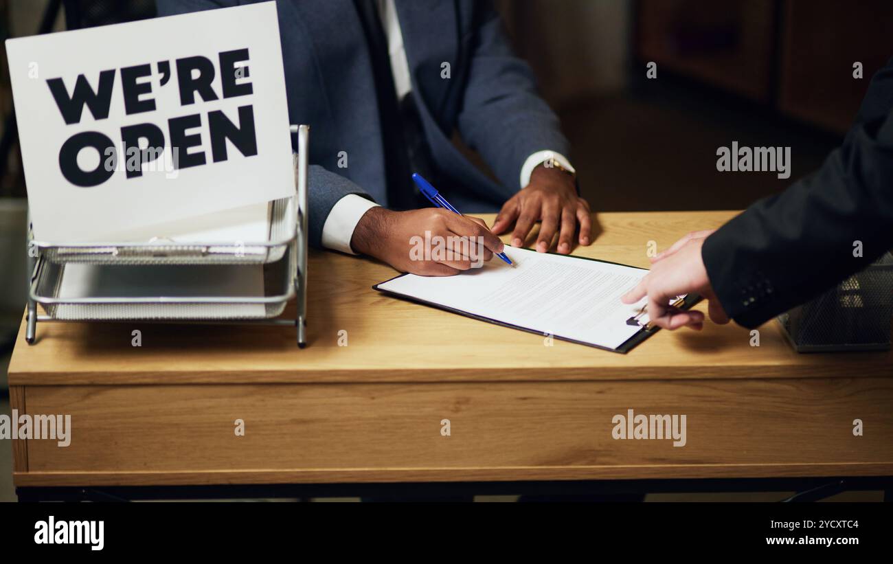 Close-up of hands as businessman signs contract while colleague points ...