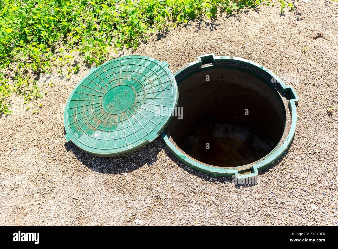 Opened unsecured sewer manhole of rural septic tank with green plastic ...