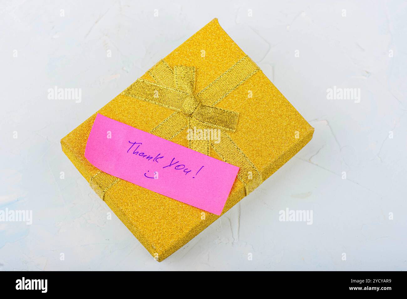 Yellow gift box with handwritten thank you note on pale blue background ...