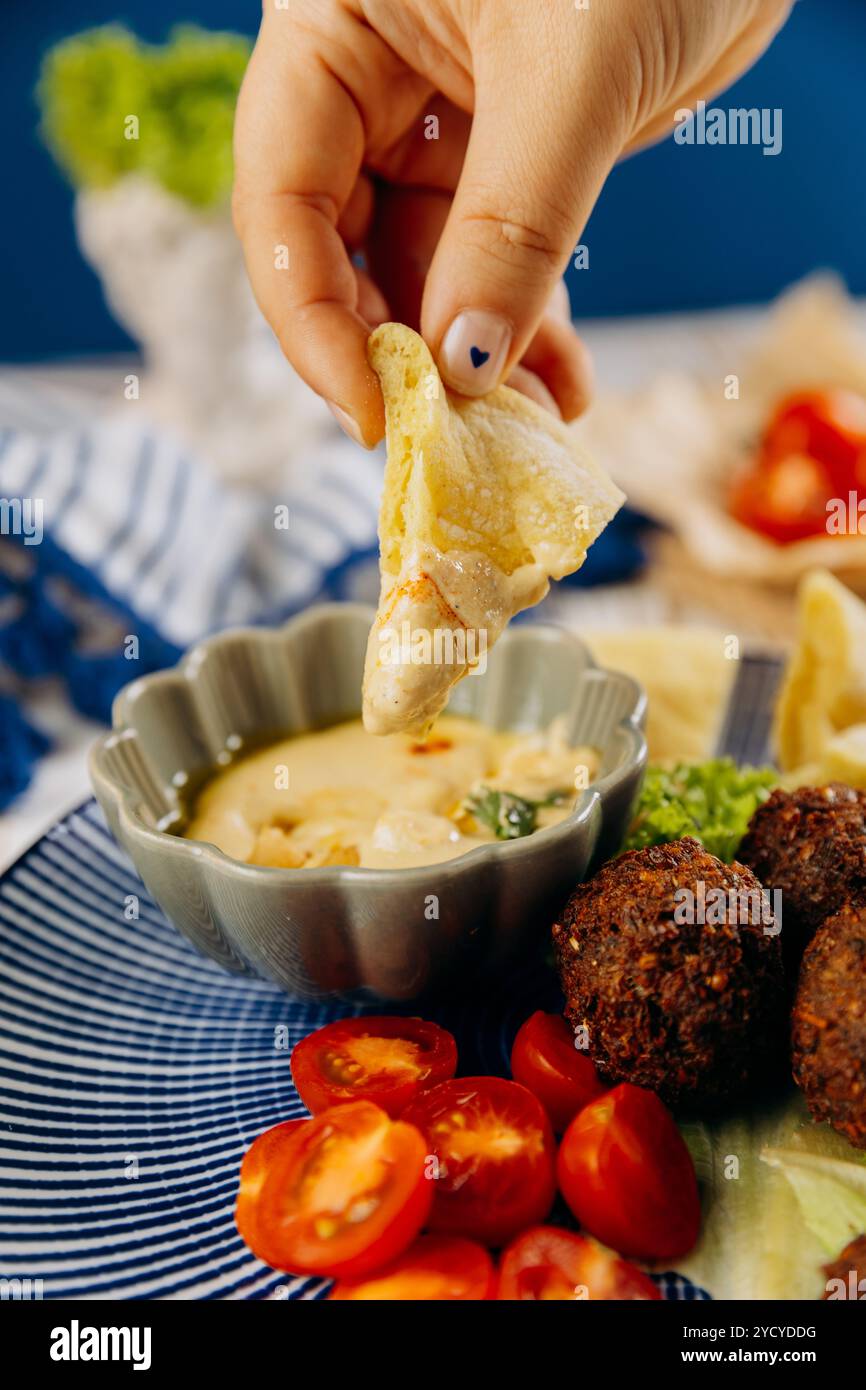 Hand dipping pita bread in creamy hummus. Perfect Middle Eastern snack ...