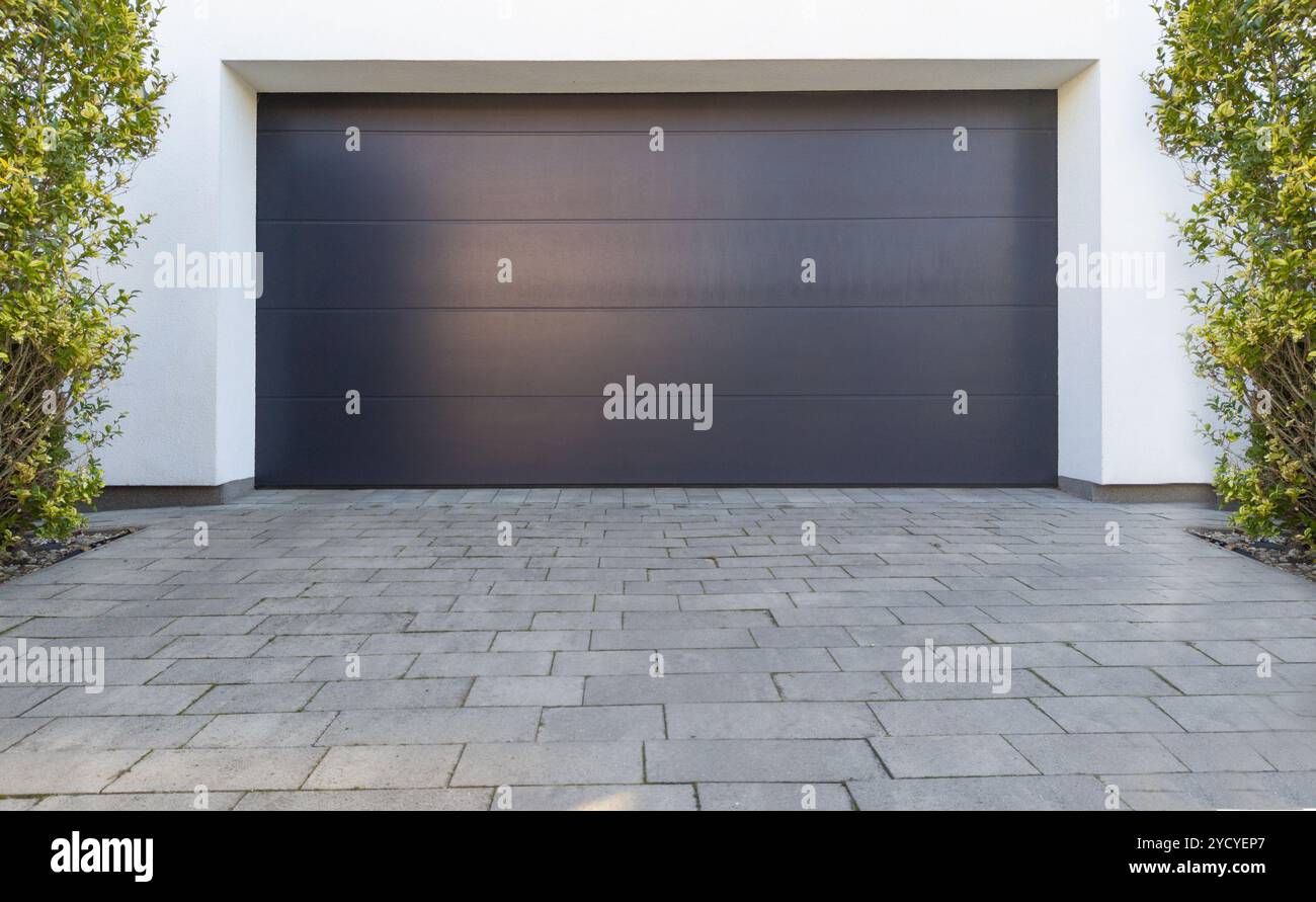 Modern Dark Garage Door with Paved Driveway Stock Photo - Alamy