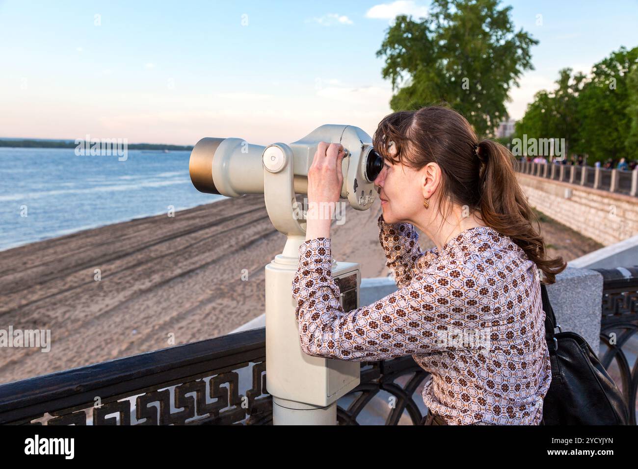 Young woman looking through the coin operated binocular Stock Photo - Alamy