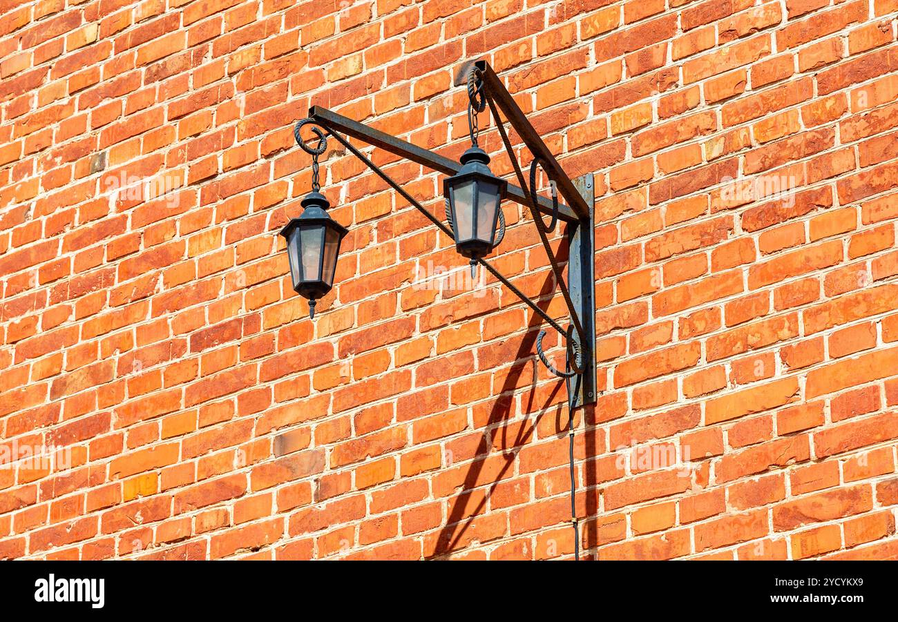 Old decorative iron street lamp hanging on the weathered brick wall ...