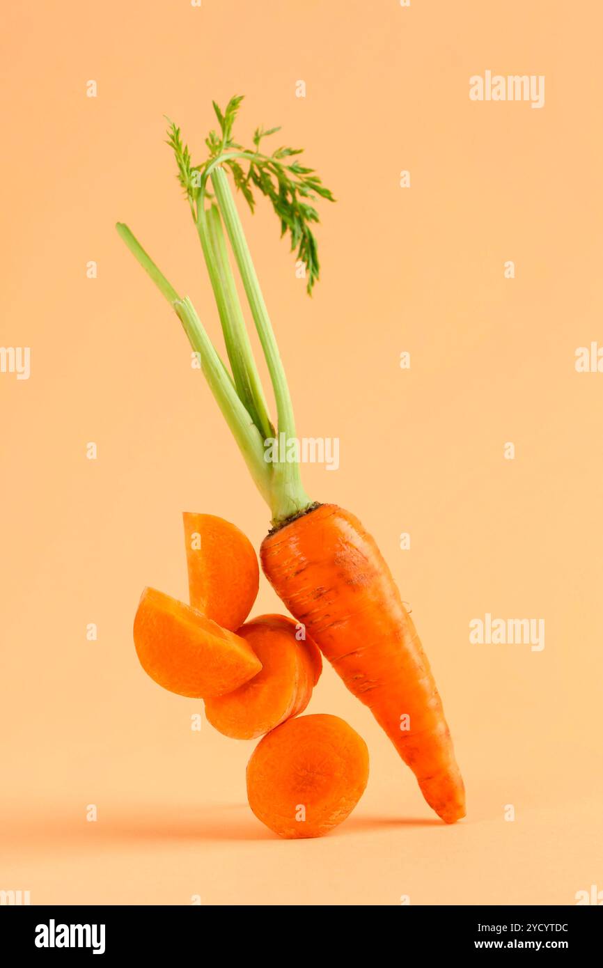 Whole and cut fresh carrots on pale orange background Stock Photo - Alamy