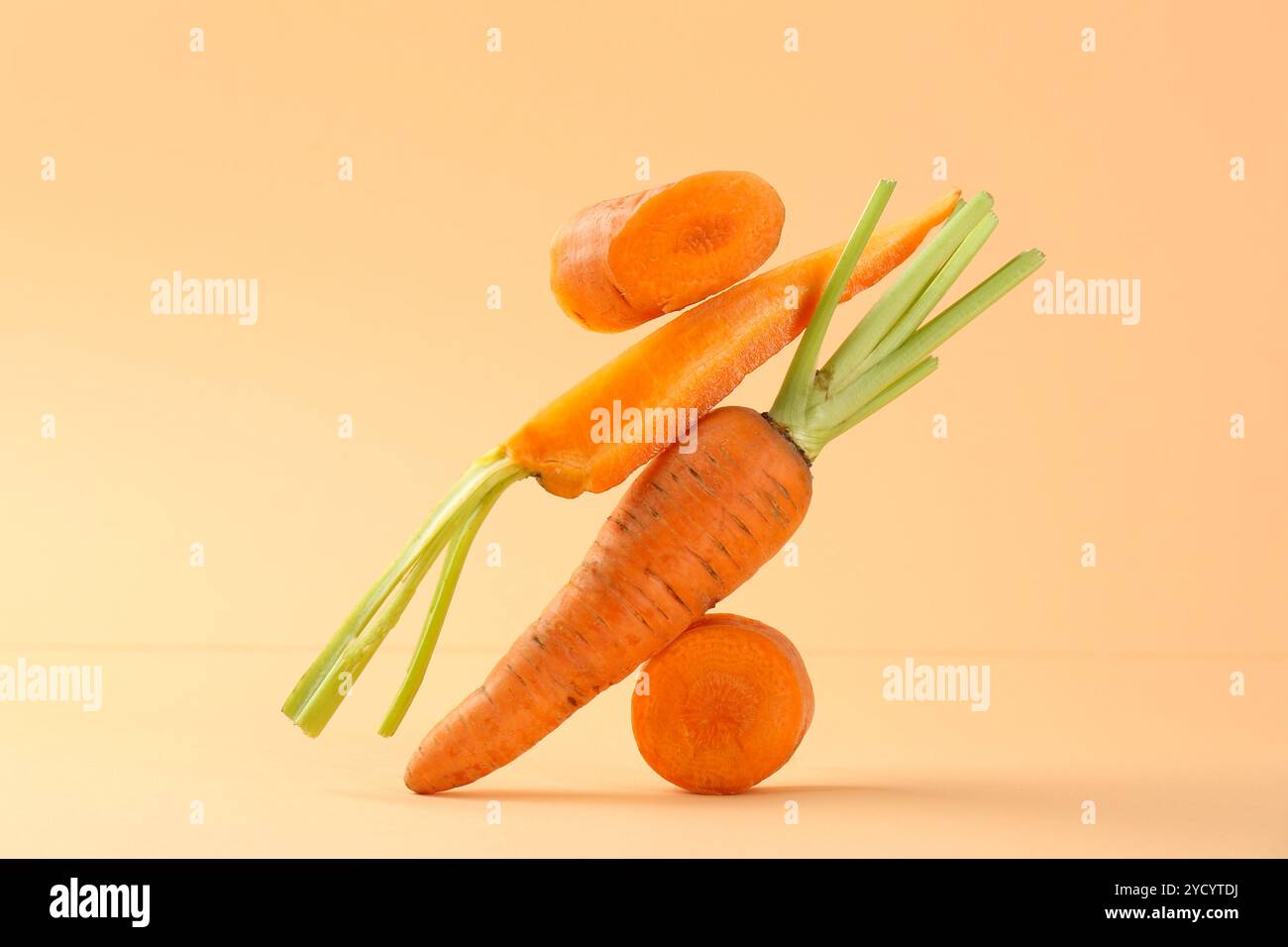 Whole and cut fresh carrots on pale orange background Stock Photo - Alamy