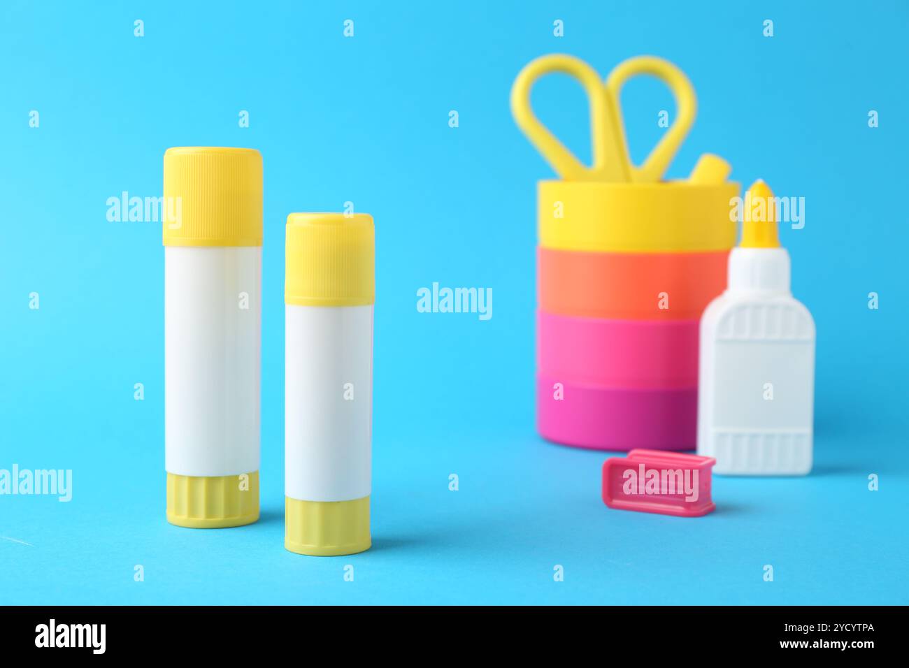Different types of glue and colorful holder on light blue background ...