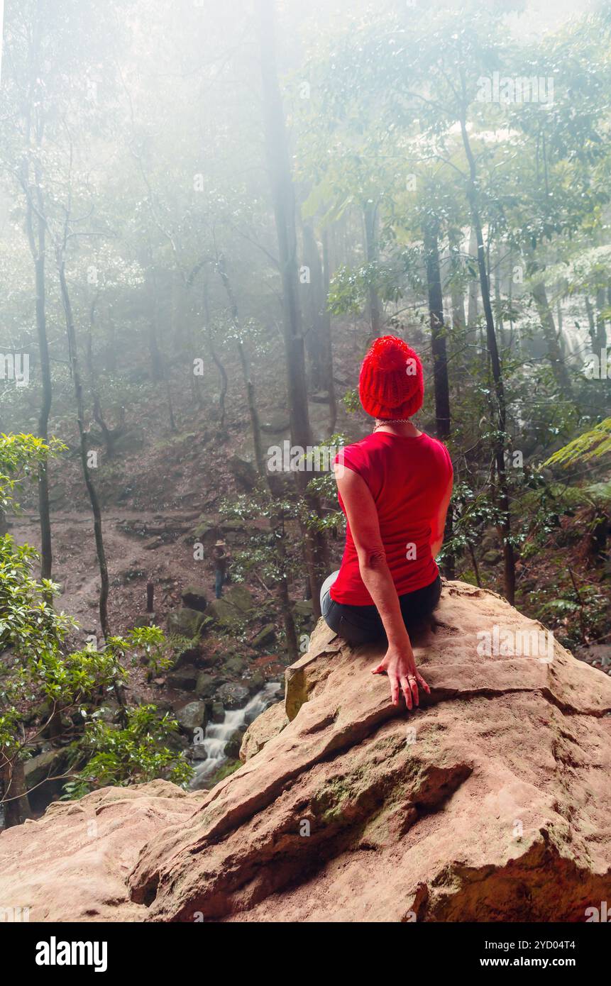 Female taking shelter from the rain in a cave overhang Blue Mountains ...