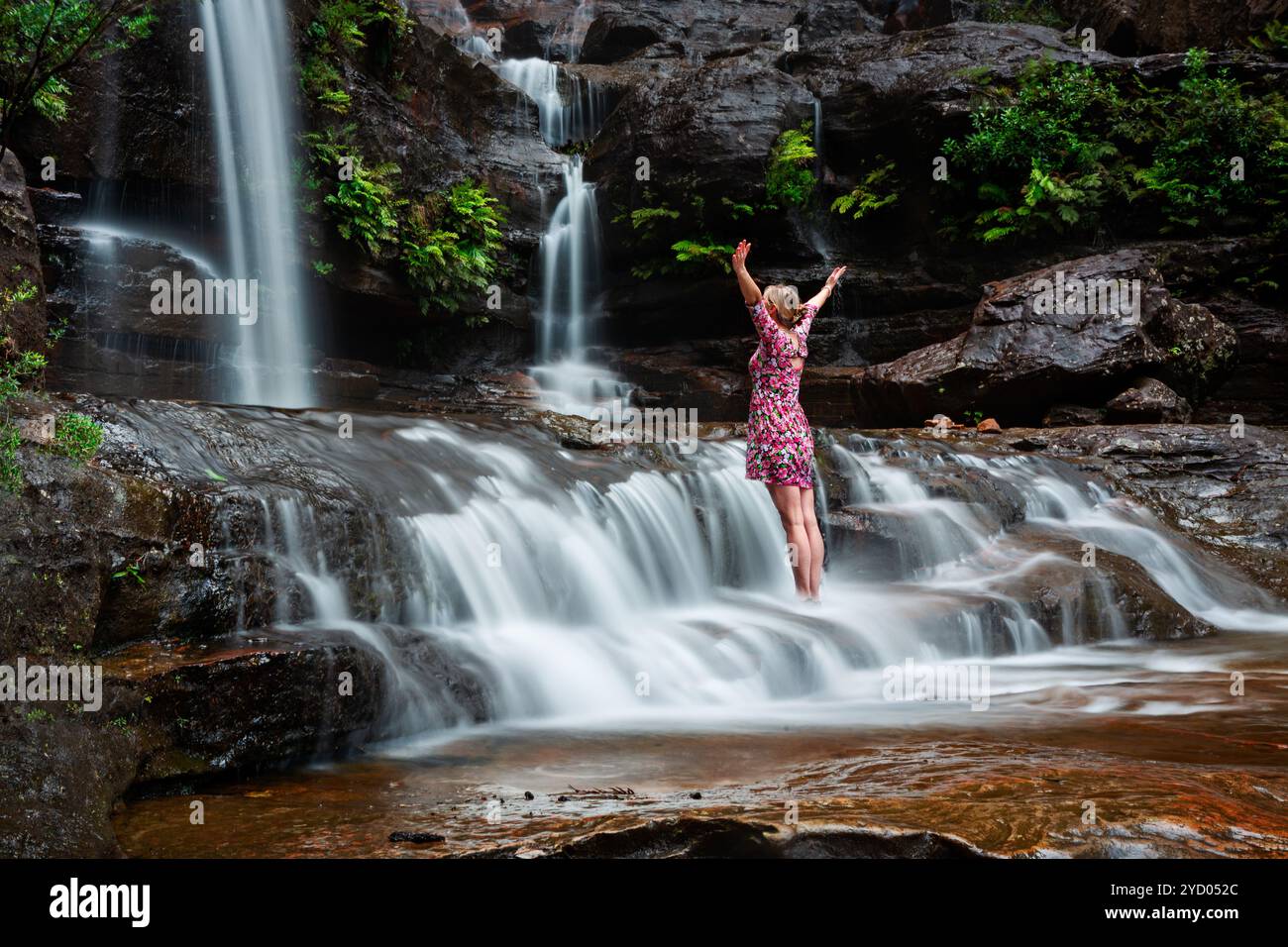 Adventurous female standing in waterfalls Stock Photo - Alamy