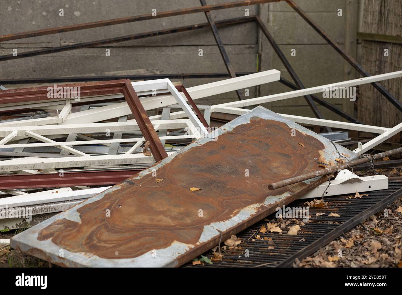 Rusty metal sheet and scattered steel frames in an outdoor yard ...