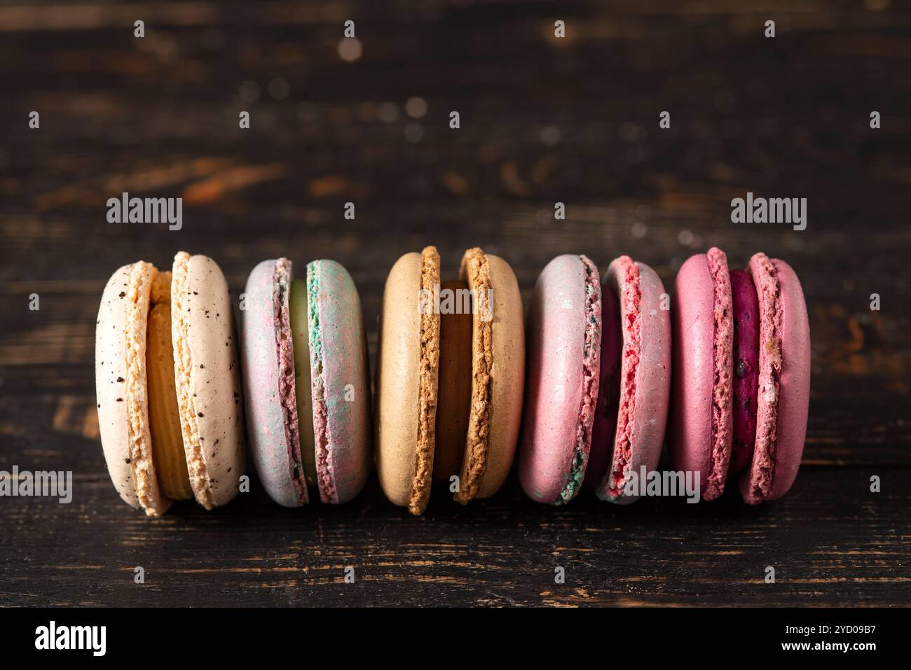 Macaron set of different flavors and colors with almond flour on a dark ...