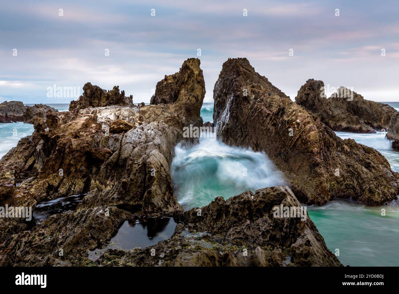 Ocean waves pushing through the dramatic jagged rock gap channel Stock ...
