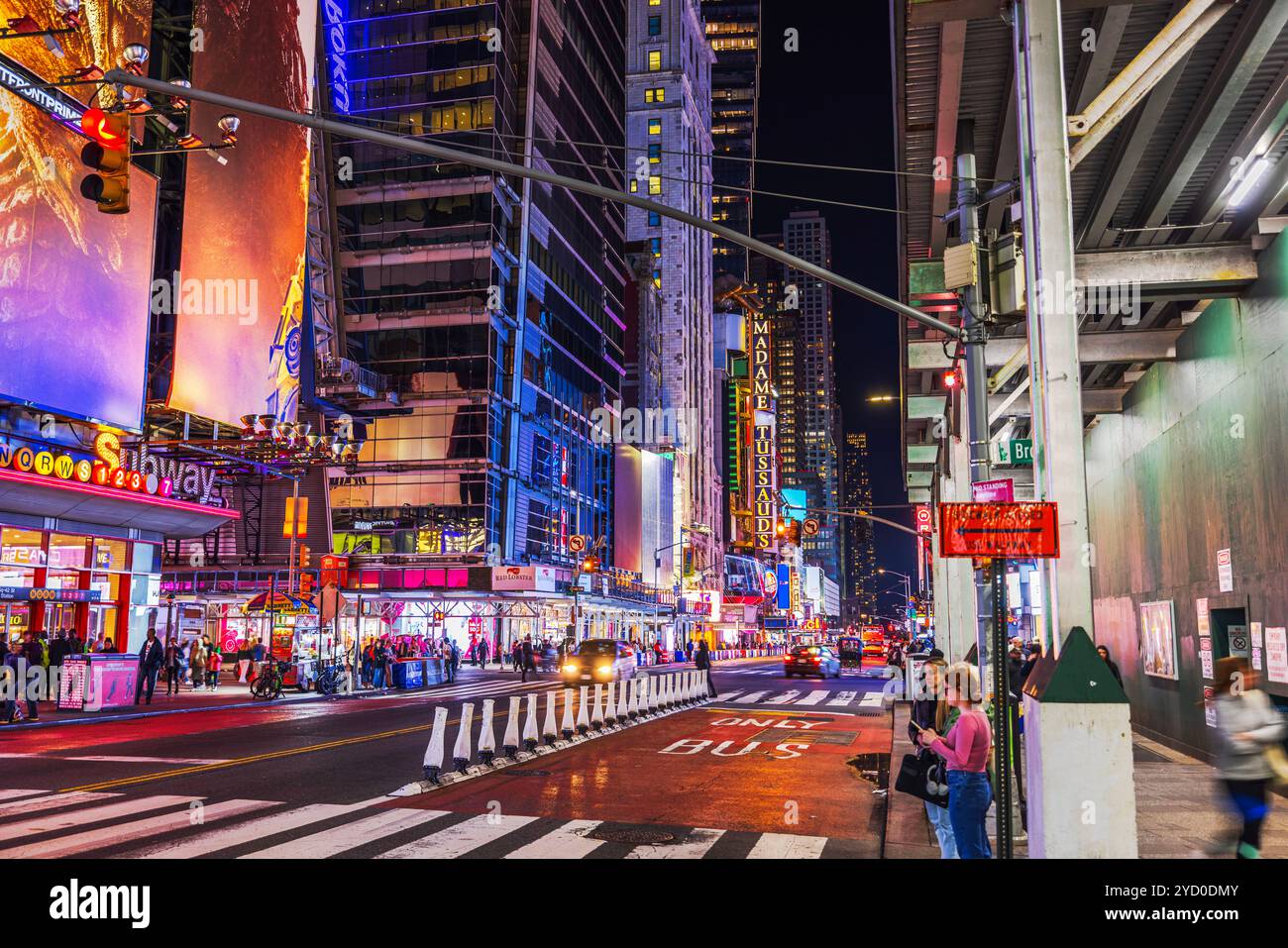 Busy Times Square street at night with neon lights, people, and Madame ...