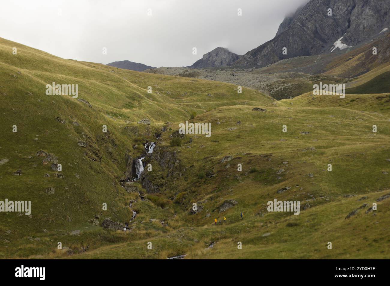 a serene mountain valley, where a small waterfall cascades down rocky ...