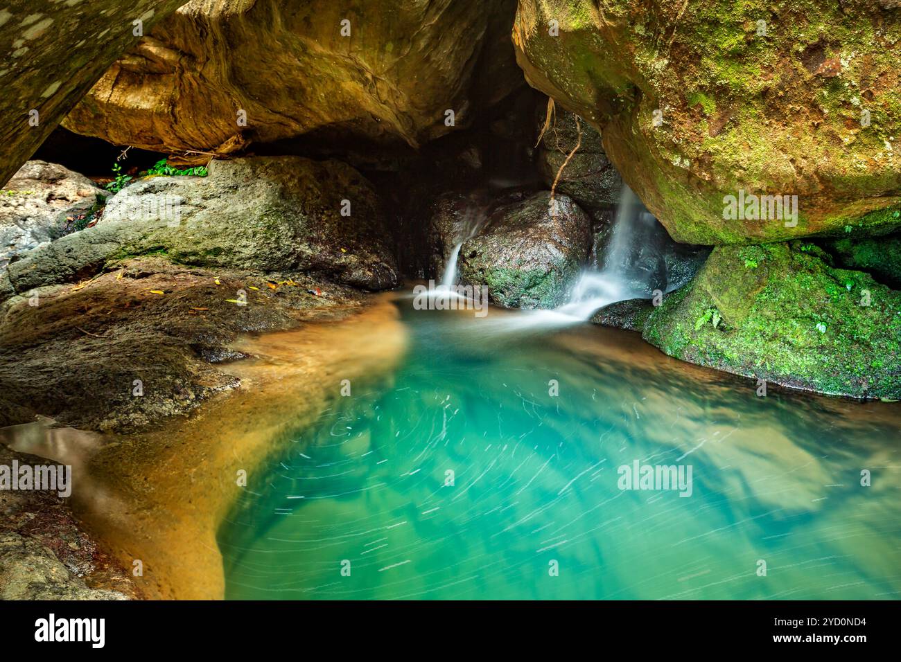 Beautiful waterfall flowing through rocky crevices into a deep pool of ...