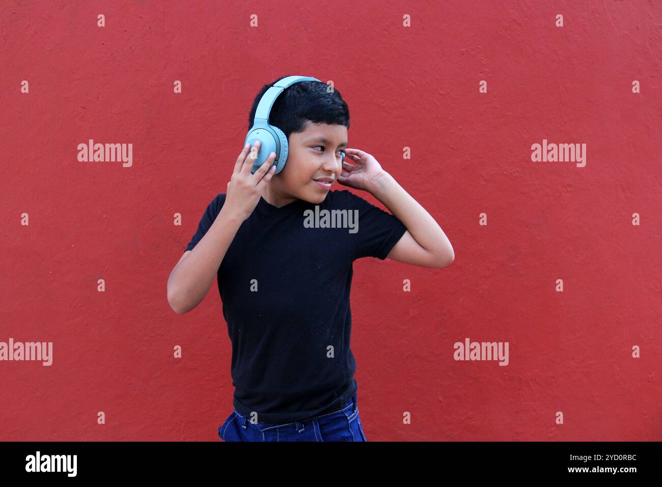 9-year-old dark-skinned Latino boy uses noise-isolating headphones due ...