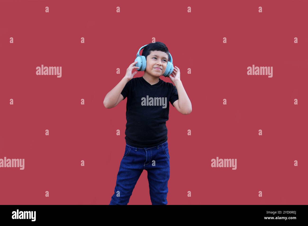 9-year-old dark-skinned Latino boy uses noise-isolating headphones due ...