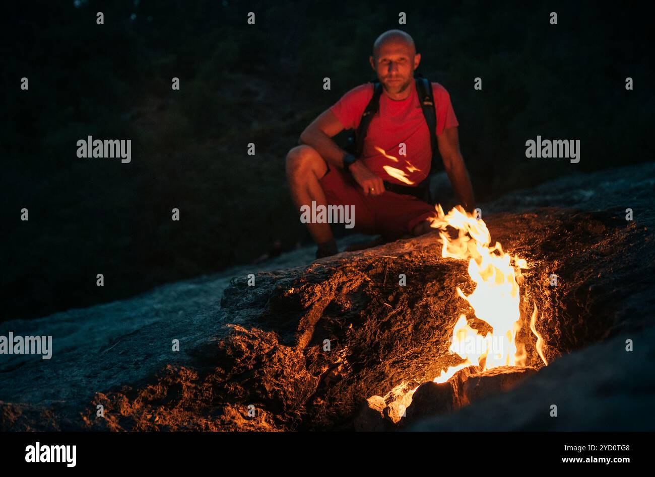 Hiker with backpack sits beside natural flames of Yanartaş, also known ...