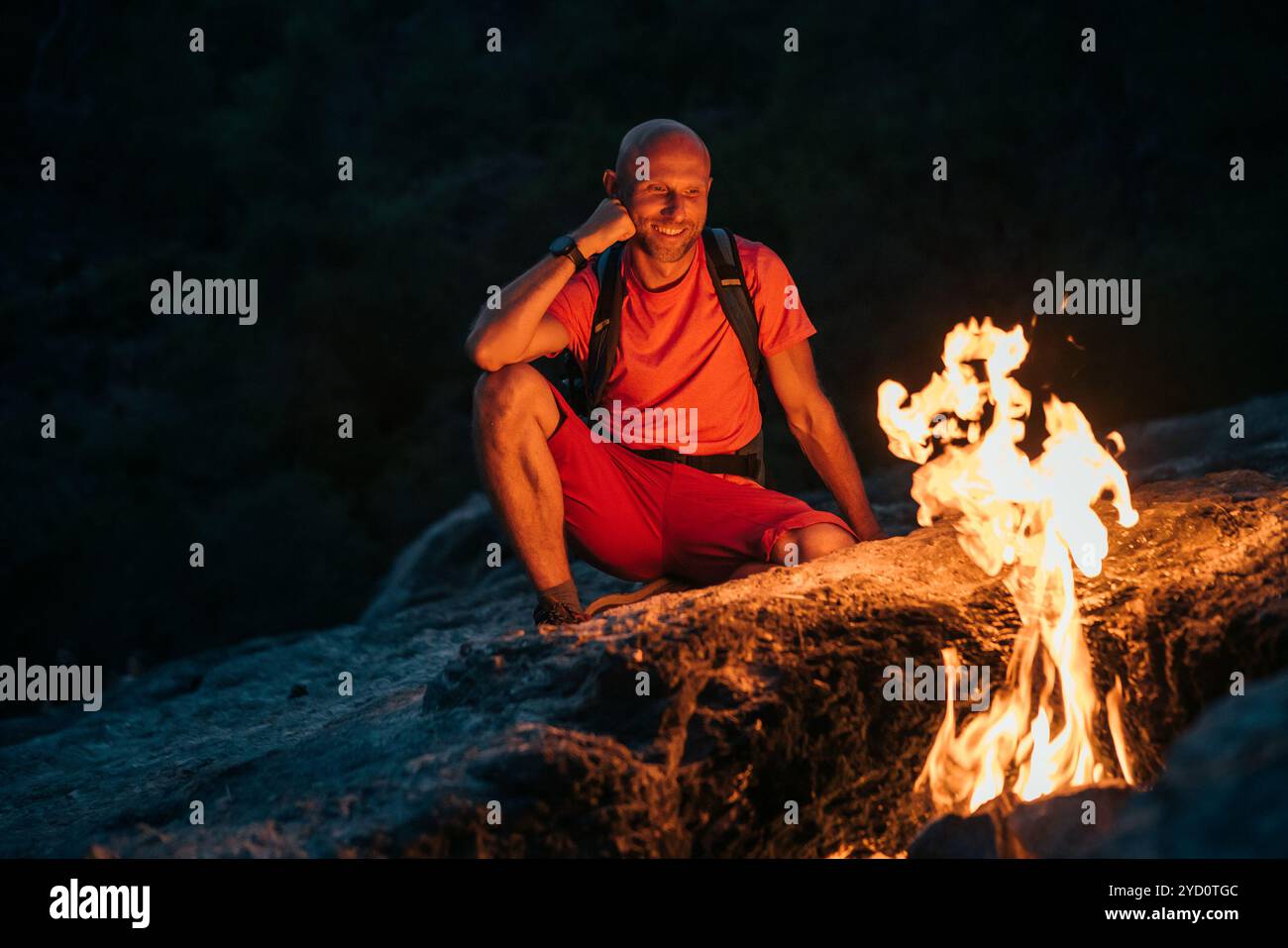 Hiker with backpack sits beside natural flames of Yanartaş, also known ...