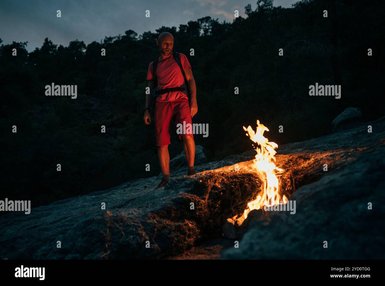 Hiker with backpack sits beside natural flames of Yanartaş, also known ...