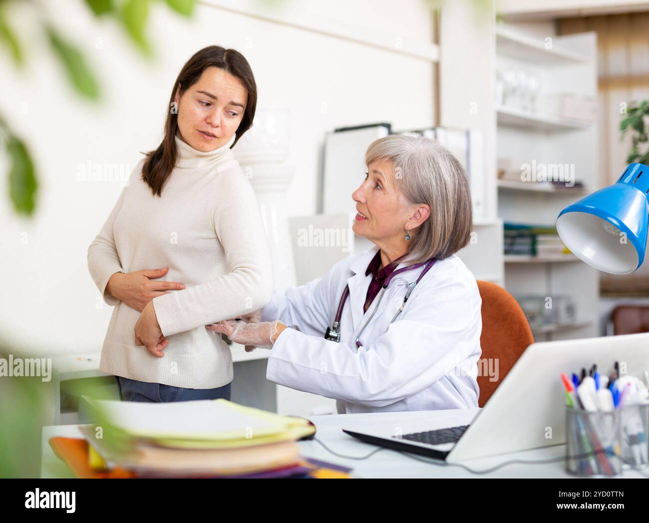 Female patient complains to doctor about abdominal pain Stock Photo - Alamy