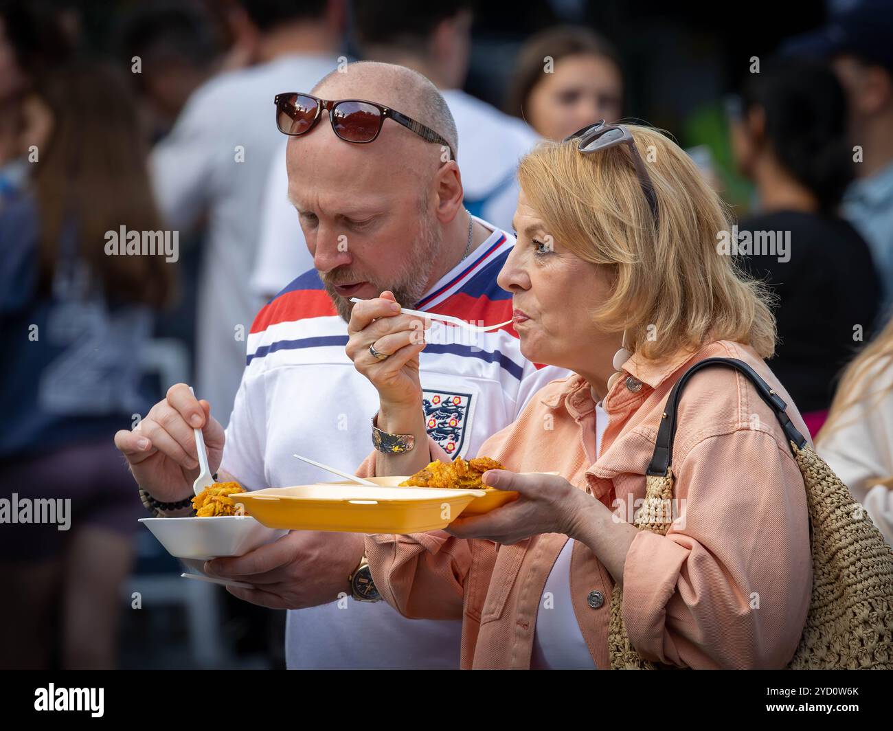 Lymm Food Festival 2024 -Man and woman eat fast food from trays in a ...