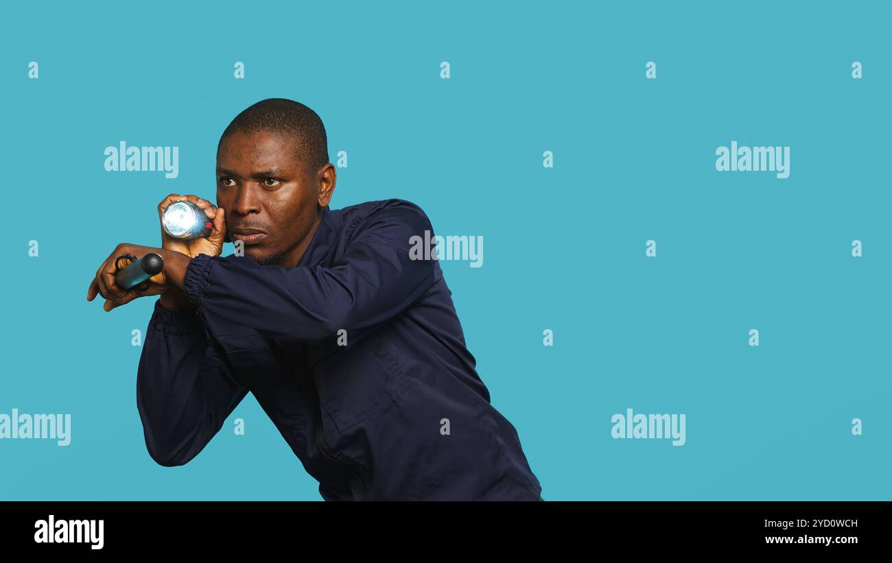 Security guard turning on flashlight and preparing baton to detect and ...