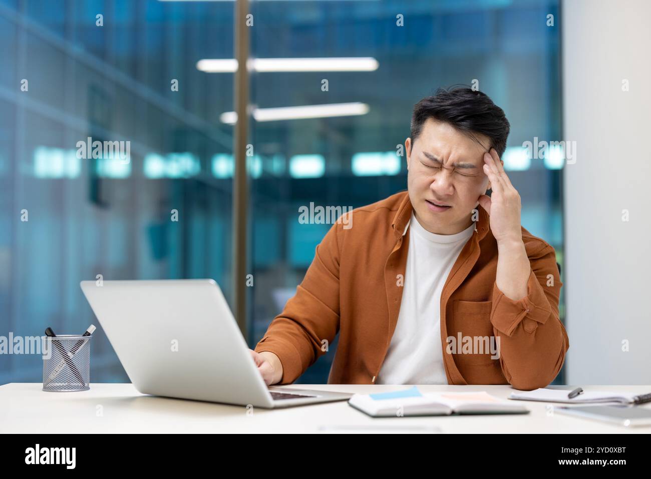 Asian businessman feeling stressed while working on laptop in office ...
