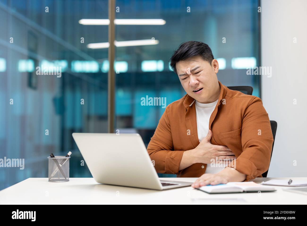 Mature Asian man feeling discomfort, placing hand on chest indicating ...