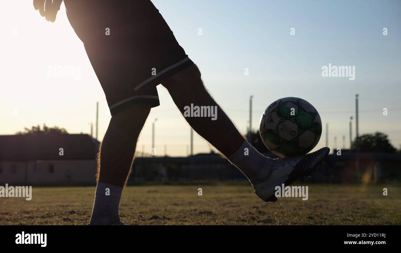 Legs of young man kicking ball at green field. Male feet of ...