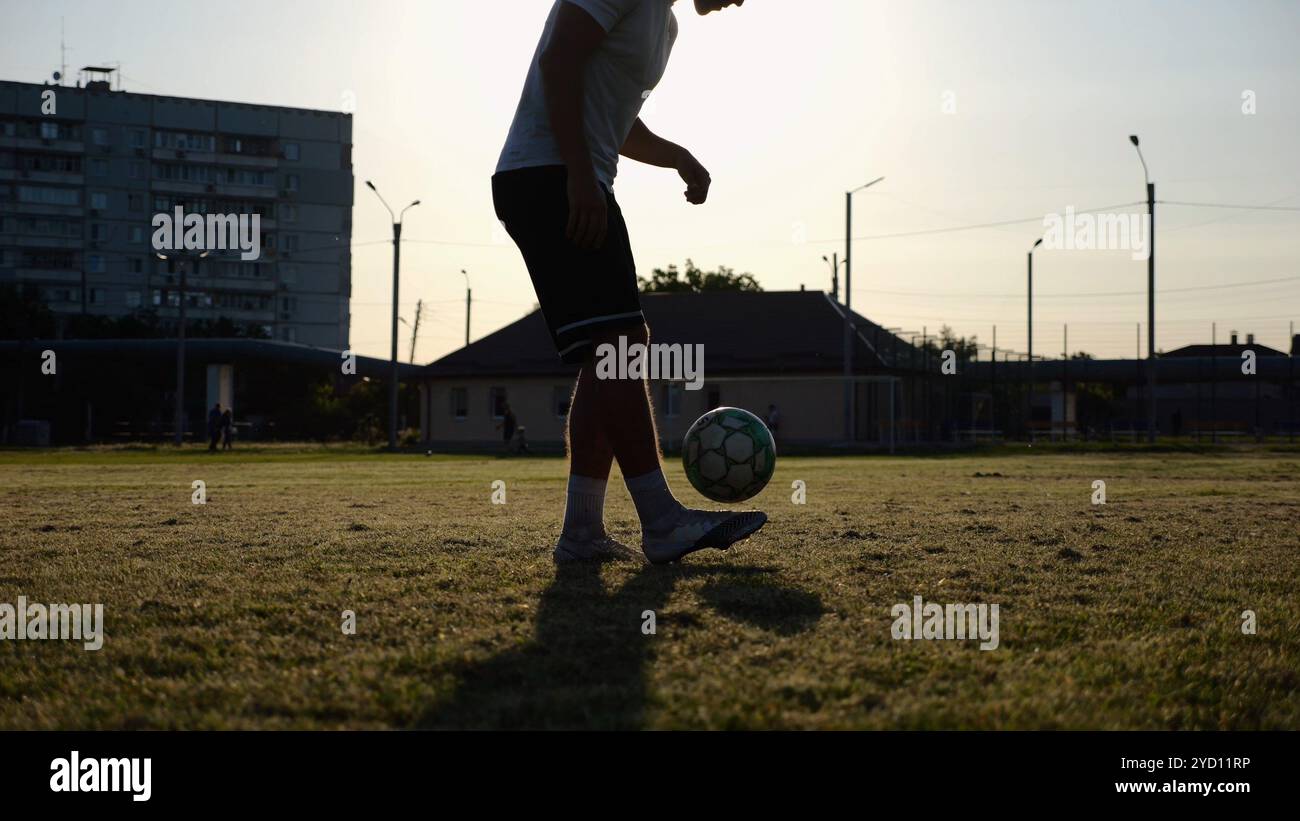 Legs of young man kicking ball at green field. Male feet of ...