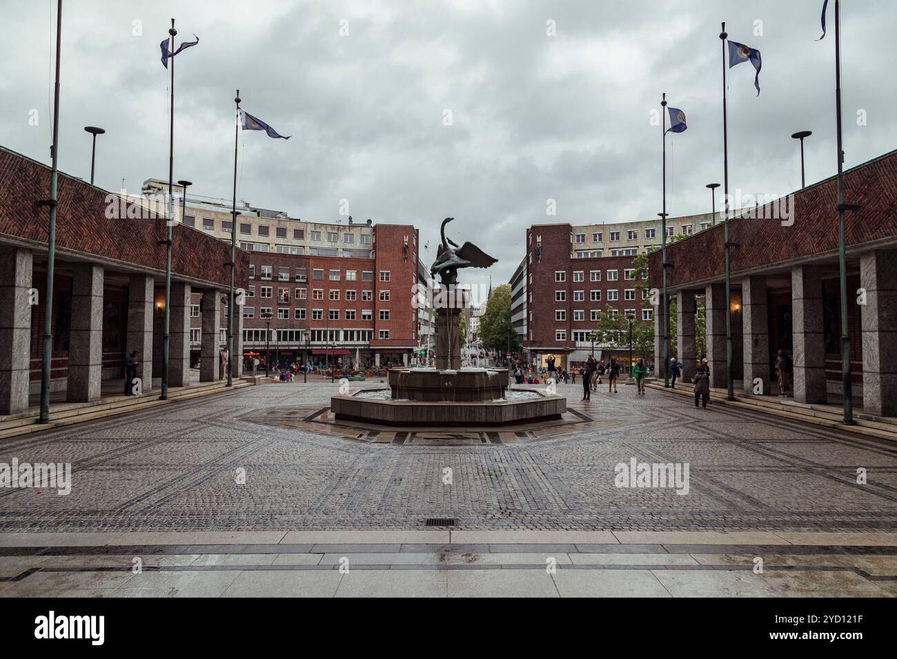 People gather in a lively public square surrounded by modern buildings ...