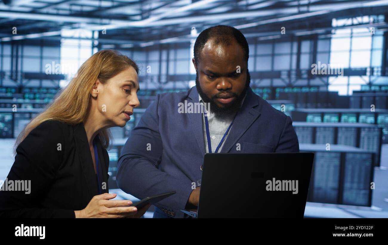 Teamworking technicians managing data center with advanced technology using devices. Coworkers ...