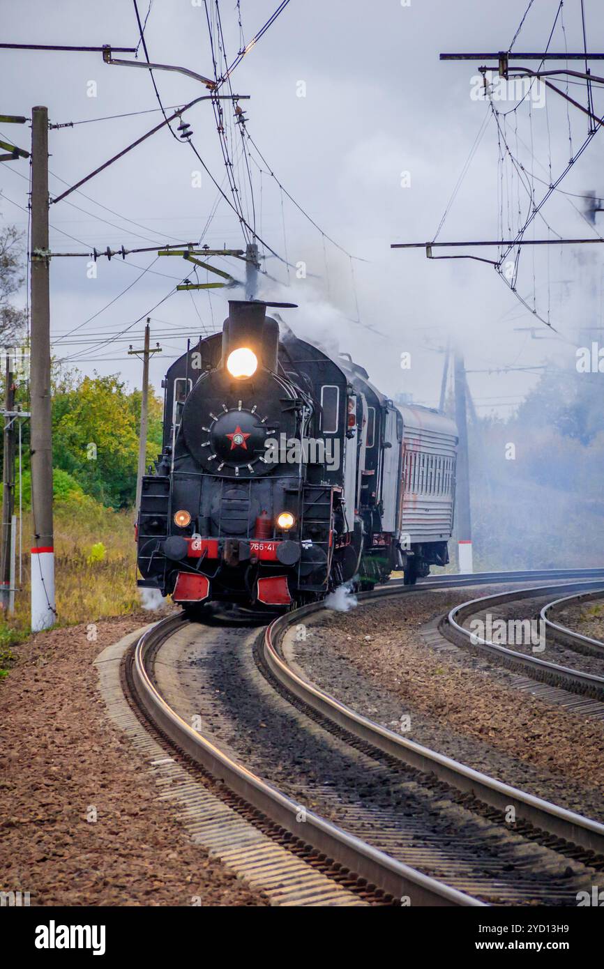 Old Russian locomotive on the railway. Old black locomotive. Smoke from ...