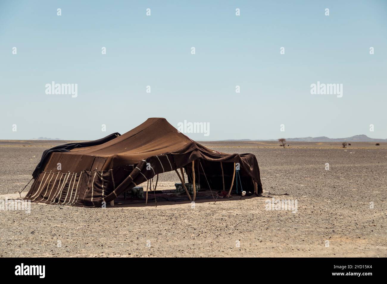 A traditional tent is set up on the arid ground of the Sahara Desert in ...